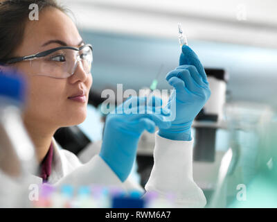 Young chinese woman wearing scientist uniform using loupe at laboratory Stock Photo - Alamy