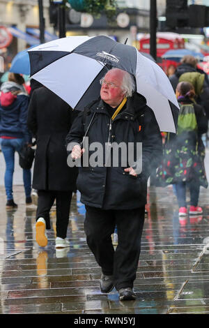A man seen walking in rain and tander storm disrupted commute. (Photo ...