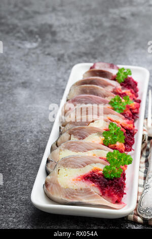 Herring slices stuffed with beetroot and potato arranged in a serving ...