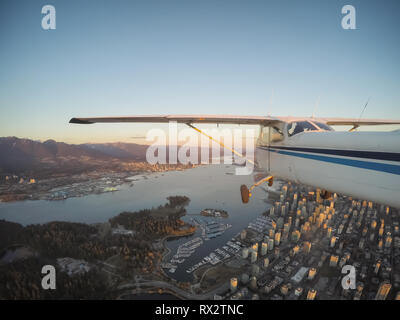 Small airplane flying over Downtown City during a vibrant sunset. Taken ...