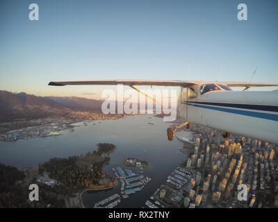 Small airplane flying over Downtown City during a vibrant sunset. Taken ...
