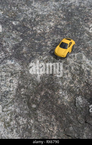 Yellow toy car falling off edge of outcrop. For falling off cliff edge ...