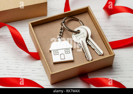 House model with key, bow, Christmas balls and gift on red background ...