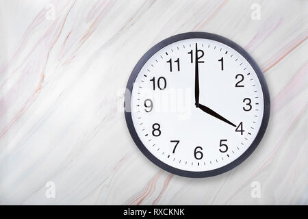 Wall clock show four o'clock on white marble texture. Office clock show ...