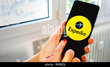 Smartphone with Expedia app logo with plane toy and red passport on ...