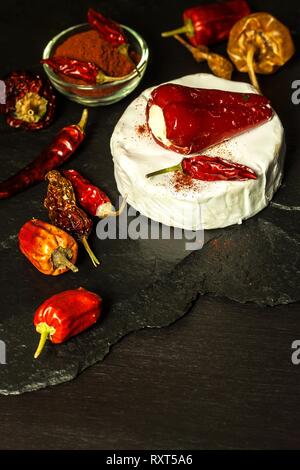 Moldy cheese and peppers on a black background. Dried chili peppers ...