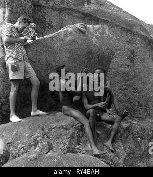 Western cameraman filming African native tribesmen performing a ...