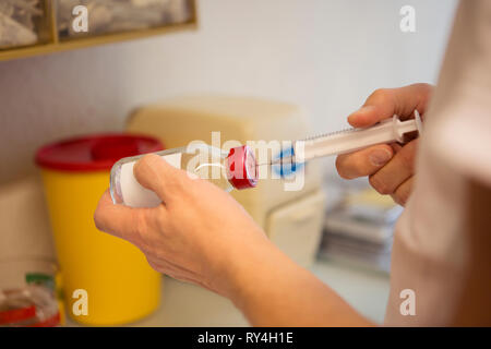Doctor drawing up medicine into a syringe in a medical treatment room ...