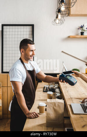 handsome cashier holding paper cups and bags wile attractive brunette ...