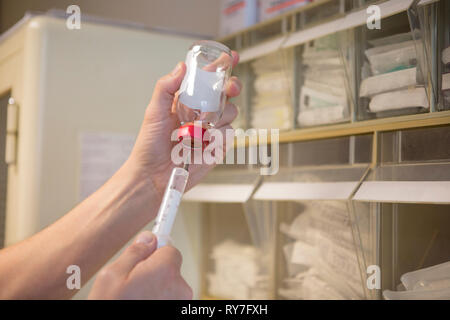 Doctor drawing up medicine into a syringe in a medical treatment room ...