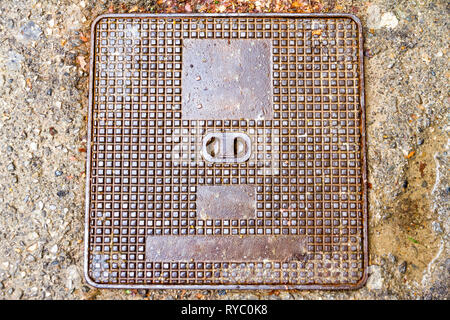 Square metal hatch in urban pavement, sewer manhole cover with marking ...