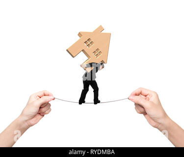 Man carrying wooden house and balancing on tightrope with hand pulling ...