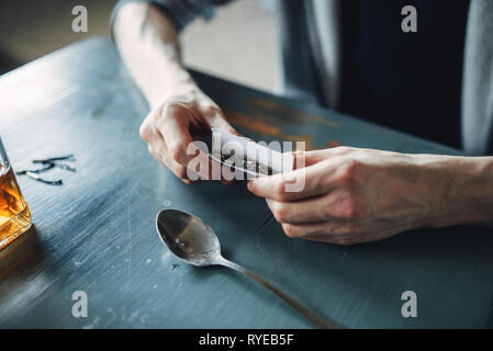 Drug addict hands prepares a dose, top view, bottle of alcohol and ...