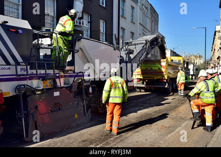 Road works. Asphalt removing machine loading powdered asphalt on the ...
