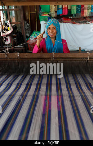 Traditional hand loom. Local muslim woman diligently weaving colourful ...