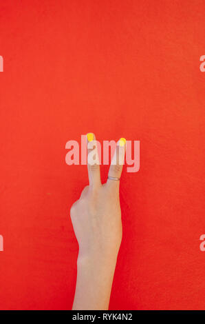 Woman hand with red nail show peace sign or number two with two fingers ...
