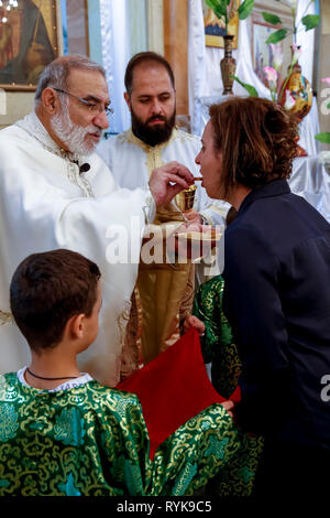 Melkite (Greek-catholic) priest giving holy communion in Sainte Foy ...