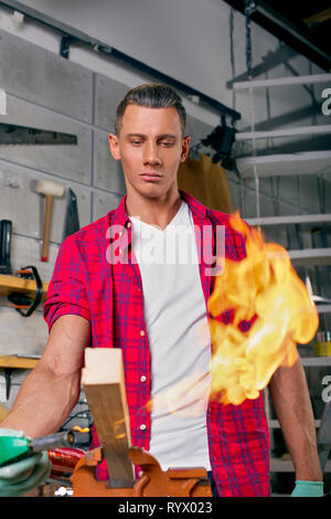 Expert carpenter burning a wood leg with a professional gas burner ...