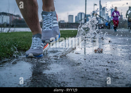 Single runner running in rain and making splash in puddle Stock Photo ...
