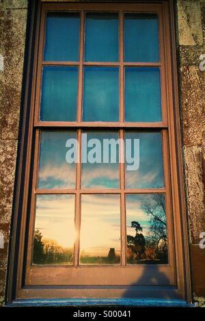 Reflection of sunset in sash window of a blue-painted Regency house ...