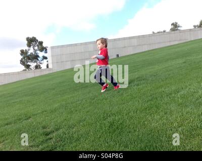 Boy running down grassy hill with mountains and forest in summer Stock ...