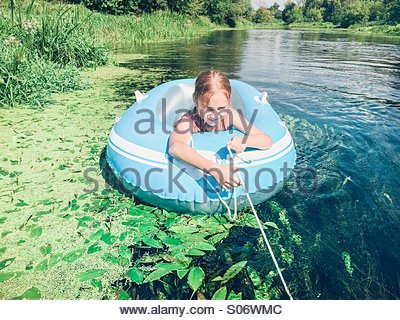 Little girl sitting in a raft on a river with lush greenery Stock Photo ...