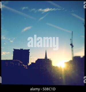 Sunrise between buildings and cranes; seen through a window Stock Photo ...