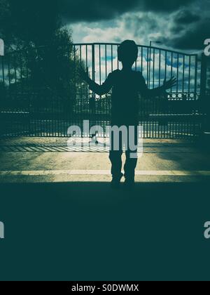 Boy standing behind a gate Stock Photo - Alamy