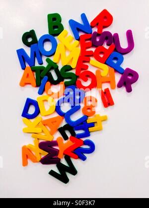 A jumble of colorful magnetic alphabet letters on a white board in a ...