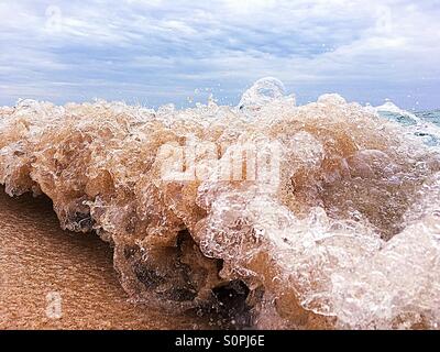 a close-up of a small wave with foam on the shore sand, seaside Stock ...
