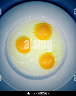 Three raw egg yolks in rustic clay bowl on white surface Stock Photo ...
