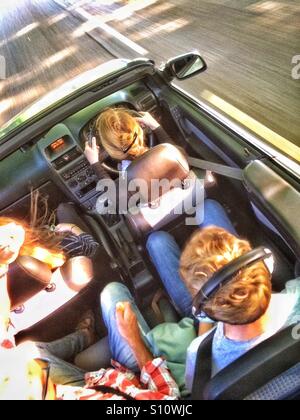 Four people in an open-topped car at a seaside resort Stock Photo - Alamy
