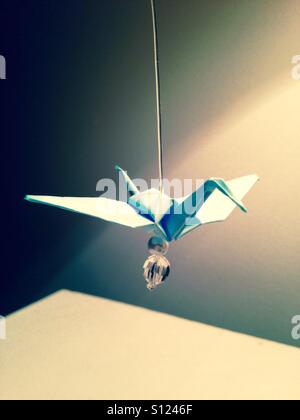 Origami art. Beautiful light blue paper crane on orange background ...