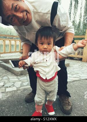 Chinese father holding son in park Stock Photo - Alamy
