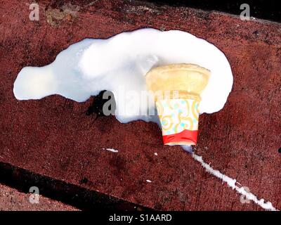 A melted ice cream cone is spilled and splattered on a blue background ...