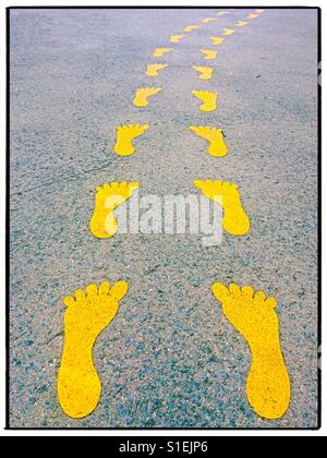 Yellow footprint painted on asphalt road. Walkway lane traffic sign ...