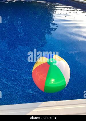 Inflatable beach ball floats in clear blue water od outdoor swimming ...