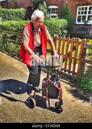 Elderly woman using a 3 wheeled walking frame Stock Photo - Alamy