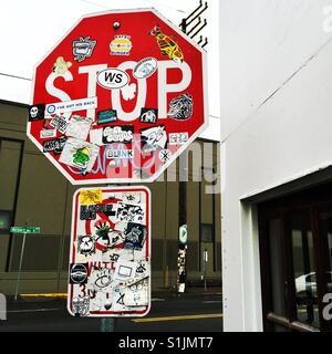 Stop sign covered in stickers and graffiti Stock Photo - Alamy