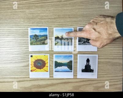 Hand choosing a photo among six options over a wood tabletop Stock ...