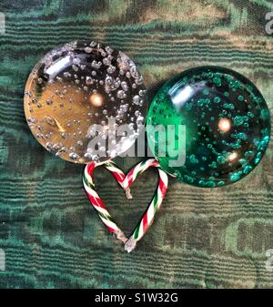 Glass with Christmas balls and candy canes on wooden background with ...