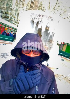 a man with a cold bundled up in a coat, knit cap, gloves and scarf ...