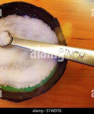 Metal spoon with a pinch of salt close up on white background Stock ...