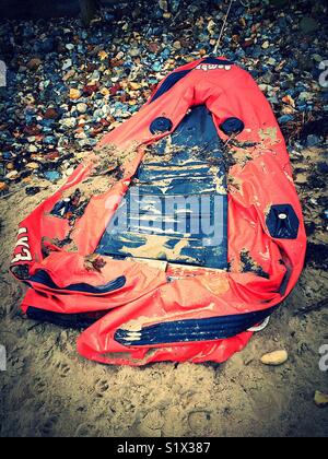 Small red dinghy boat washed up on beach Stock Photo - Alamy
