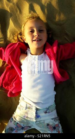 Girl making sand angel Stock Photo - Alamy