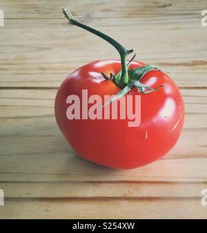 A bright red tomato has ripened on the windowsill as a houseplant ...