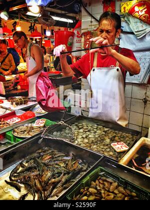 A fishmonger weighs produce using a traditional Chinese steelyard ...