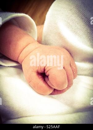 Newborn clenched fist of baby's hand with tiny fingers, touching her ...