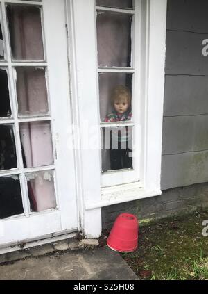 Scary doll toy looking out the window at halloween Stock Photo - Alamy