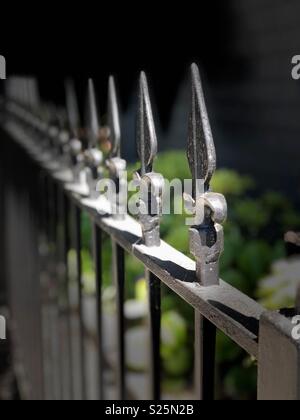 Wrought iron arrow tipped garden fence with leaf caught in cobweb in ...